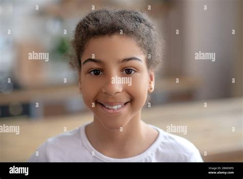 Cute Curly Haired Girl Smiling And Looking Pleased Stock Photo Alamy