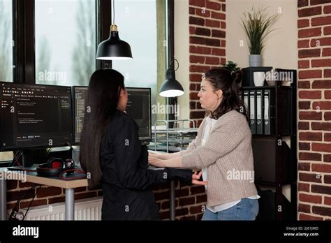 company programmers standing near desk with multiple monitors on top of it network developers