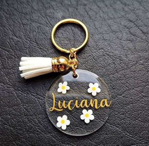 A Glass Keychain With Flowers And The Word Luciana Written In Gold On It