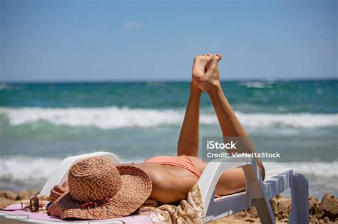 하얀 모자를 쓰고 바다를 배경으로 해변에서 일광욕을 하는 알아볼 수 없는 기대어 앉는 여성 클로즈업 35 39세에 대한 스톡 사진 및 기타 이미지 Istock