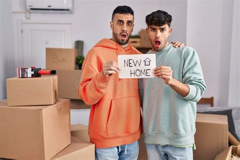Young Hispanic Gay Couple Moving To A New Home In Shock Face Looking