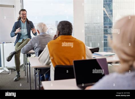 A Young Professor Teaching A Lesson In A Classroom A Small Group Of
