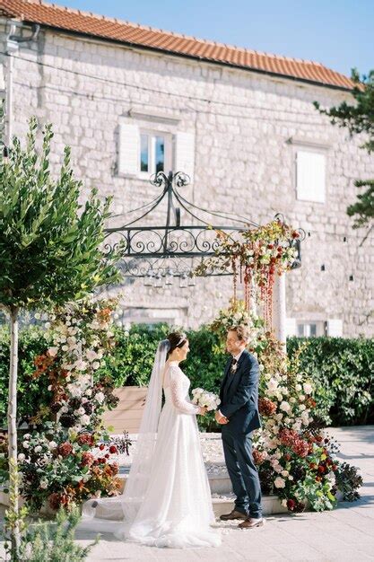 Premium Photo Bride And Groom Stand Holding Hands Near The Wedding