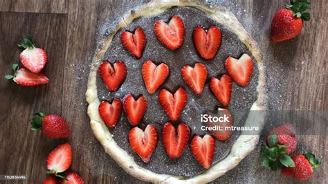 딸기와 설탕이 들어 있는 홈메이드 초콜릿 피자 헤이즐넛 초콜릿으로 채워진 구운 피자 크 러스트와 낭만적 인 붉은 사랑의 심장 모양의 딸기 딸기 열매를 얹은 후 슬라이스 하