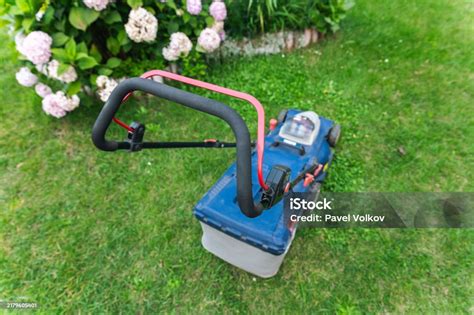 잔디가 무성한 잔디밭에 잔디 깎는 기계 뒷면에 부착된 잔디 수집 가방으로 잔디 깎는 기계를 밉니다 잔디를 일정한 높이로 하여 깔끔하고 균일한 잔디 외관을 제공합니다 가솔린에