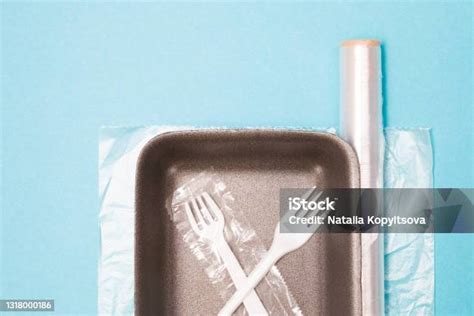 파란색 배경에 다양한 일회용 플라스틱 포장 식품 트레이 플라스틱 테이프 롤 및 냉동 식품을위한 가방 일회용 포크와 음주 튜브 환경 오염 개념 용기 제작물에 대한 스톡 사진