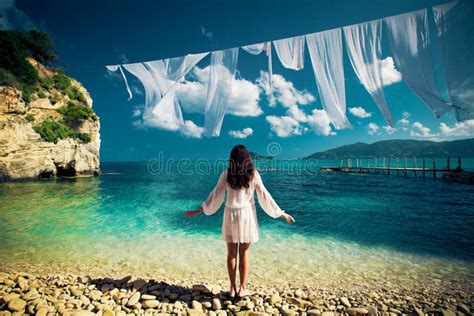 Mujer Morena Joven En El Vestido Blanco Del Verano Que Se Coloca En La Playa Y Que Mira Al Mar