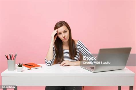 우려 화가 피곤된 여자 손에 앉아 파스텔 핑크 배경에 고립의 현대 Pc 노트북과 흰색 책상에서 작업을 기대 하 고 성과 비즈니스 경력 개념입니다 광고에 대 한 공간을 복사