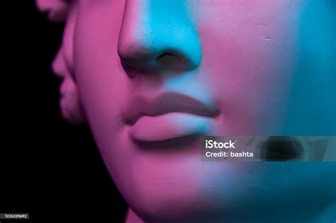 검은 배경에 예술가를위한 인간의 머리의 고대 동상의 다채로운 석고 사본 보기 입술을 닫습니다 인간의 얼굴의 석고 조각 색조의 블루와 퍼플 웹 펑크 초현실적 인 스타일의