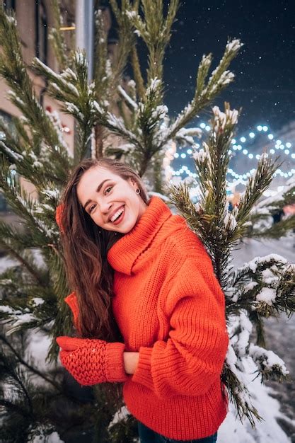 Joven Mujer Posando Cerca Del árbol De Navidad En La Calle Foto Gratis