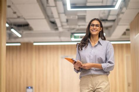 Premium Photo Woman With Folder Smiling At Camera Indoors