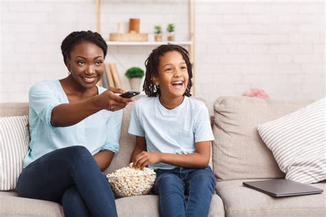 Mulher Africana E Garota Assistindo TV Lanche Foto De Stock