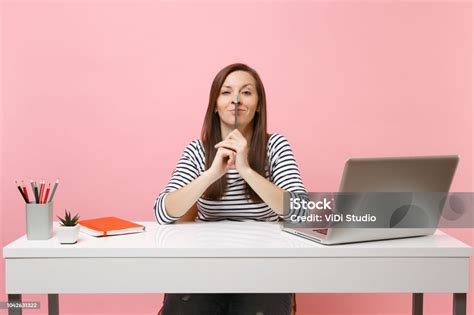 캐주얼 옷 들고 앉아 연필 파스텔 핑크 배경에 고립의 현대 Pc 노트북과 흰색 책상에서 일에에서 재미 있은 여자 성과 비즈니스 경력 개념입니다 광고에 대 한 공간을 복사