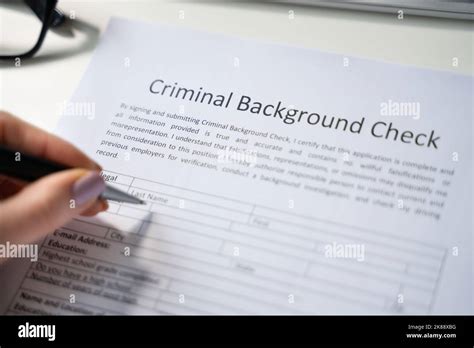 Close Up Of Human Hand Filling Criminal Background Check Application Form With Pen Stock Photo