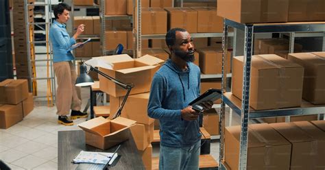 소기업 소유주는 판지 상자의 바코드를 스캔하고 창고 공간에서 상품 재고를 처리하는 작업을 하고 있습니다 남자 노동자가 화장실 선반에서 소포를 꺼내 확인하고 있다 사진