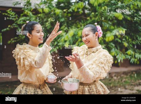 Young Smiling Women Dress In Beautiful Thai Costumes Splashing Water In