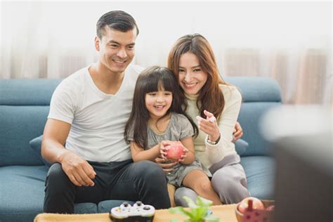 소파 딸 걸릴 애플에 반면에 아버지와 어머니와 집에서 Tv를 보고 있는 앉아 앉아 가족 시간 젊은 부모와 딸 웃 고 가족에 대한