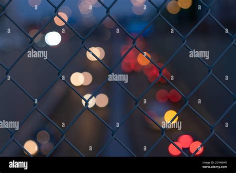 A Scene Of Cars And City Roads Shot Through Iron Netting At Night
