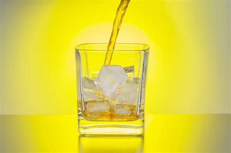 노란색 광원의 배경에 얼음이 있는 투명 한 유리에 위스키를 붓고 0명에 대한 스톡 사진 및 기타 이미지 0명 각얼음 갈색 Istock