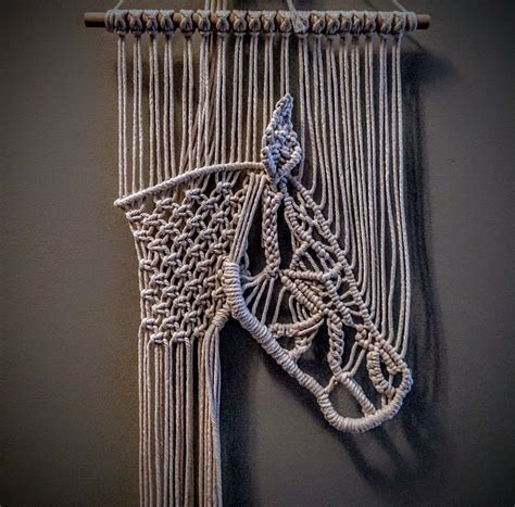 a piece of art made out of rope and beads hanging from a hook on the wall