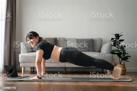 거실에서 아시아 통통한 여자는 컴퓨터로 온라인 요가 수업을 연습합니다 노트북에서 명상 훈련 수업을 하는 여성 25 29세에 대한