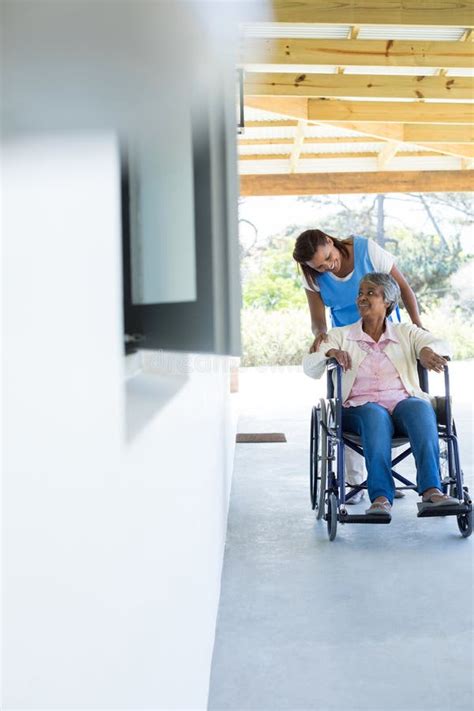 Female Doctor Pushing Happy Senior Patient In Wheelchair Stock Image