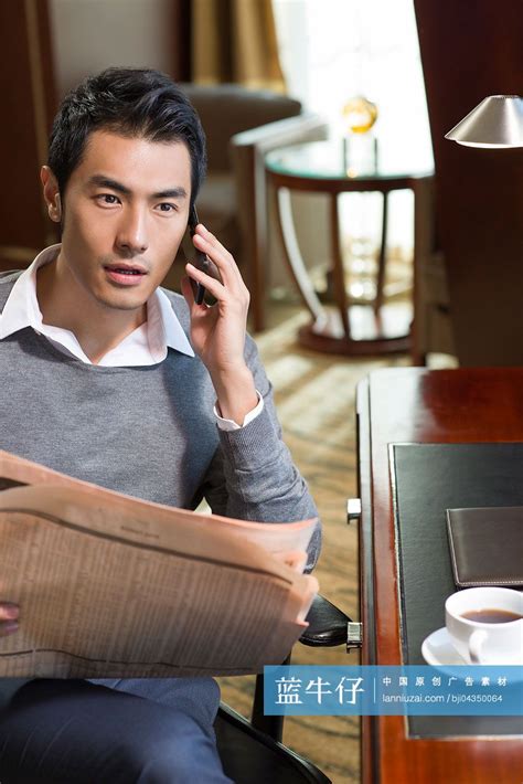 年轻商务男士边看报纸边打电话 蓝牛仔影像 中国原创广告影像素材