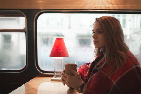 Winter Portrait Of A Girl With A Cup Of Coffee In Her Hands Sits In A