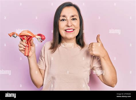 Middle Age Hispanic Woman Holding Anatomical Model Of Female Genital