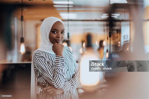 흑인 여성 무슬림이 히잡을 쓰고 현대적인 비즈니스 사무실에 서 있는 특성 사무실에 대한 스톡 사진 및 기타 이미지 Istock