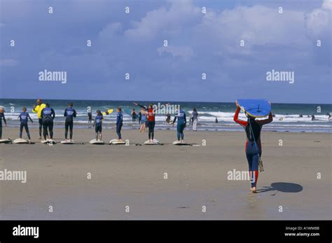 Learner Surfers Stand On The Beach With Their Boards Surf School
