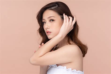 젊은 아시아 여자 자연 뷰티 메이크업 패션 모델 건강 웰빙 아름다운 소녀 스킨 케어 및 얼굴 치료 베이지 색 배경에 격리 텍스트에 대한 복사 공간을 제공합니다 건강관리와