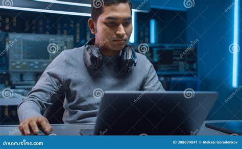 Portrait Of Software Developer Hacker Programmer Sitting At His Desk And Working On Laptop