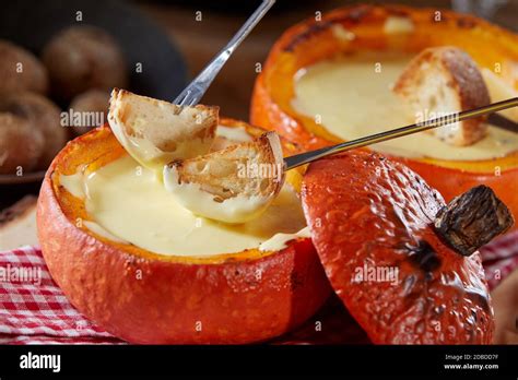 Traditional Swiss Fondue With Melted Raclette Cheese Served In A Hollow
