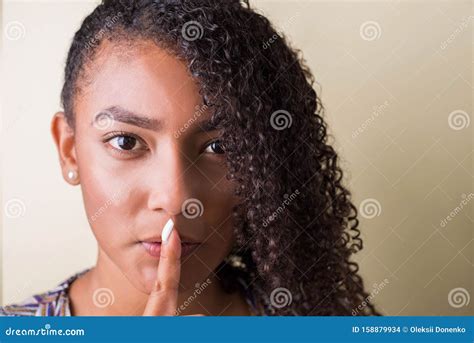 Hispanic Girl Holding A Finger To Her Mouth Showing Silence In The