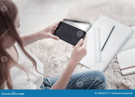 Menina Que Senta Se No Assoalho E Que Guarda Seu Telefone Imagem De