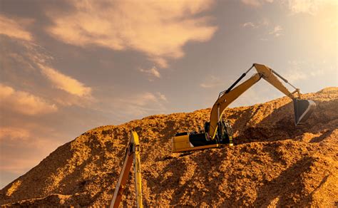 バックホウは紙の生産工場で巨大なおが屑の山に取り組んでいます木材チップを掘る掘削機のバケツ空に対するパルプミルからの木材チップの山パルプおよび