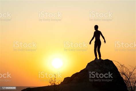 산의 일몰에 큰 돌에 혼자 서 여자 등산객의 실루엣 저녁 자연에서 높은 바위에 여성 관광객 관광 여행 및 건강한 라이프 스타일