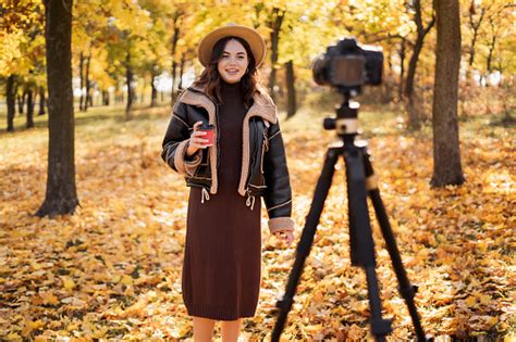 가을 초상화 세련된 여자는 블로그를 위해 비디오 콘텐츠를 녹화하고 노란 나뭇잎 배경에 둥근 모자를 쓰고 있다 18 19세에 대한 스톡 사진 및 기타 이미지 Istock