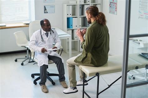 Paciente Masculino Joven Sentado En Una Litera Frente A Un Médico
