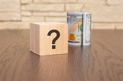 Premium Photo Wooden Cube With A Question Mark And Dollar Bills On A