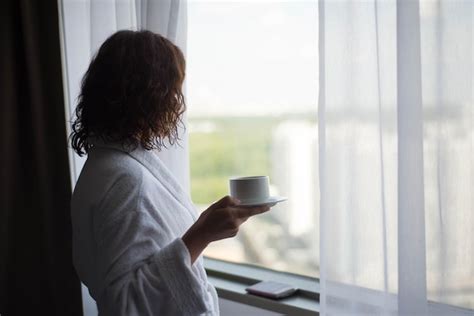 Premium Photo Cute Woman Drinks Coffee And Looks Through The Window