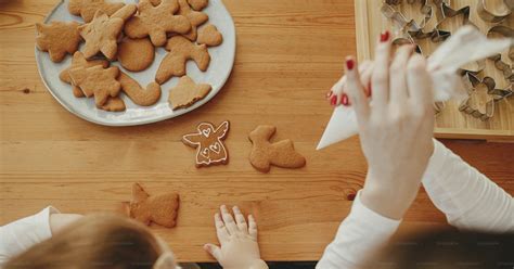 귀여운 딸과 어머니는 크리스마스 진저 브레드 쿠키를 나무 테이블에 장식하고 있습니다 평면도 가족 시간 크리스마스 휴가 준비