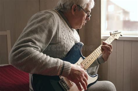 Senior Man Is Playing Guitar Elderly Man Sitting On The Sofa And
