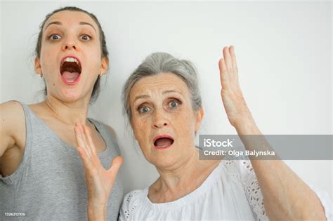 그녀의 선임 모터와 감정적 인 성인 딸은 비명을 지르고 카메라를보고 흰색 배경에 재미를 다른 연령 세대의 미친 가족 어머니의 날
