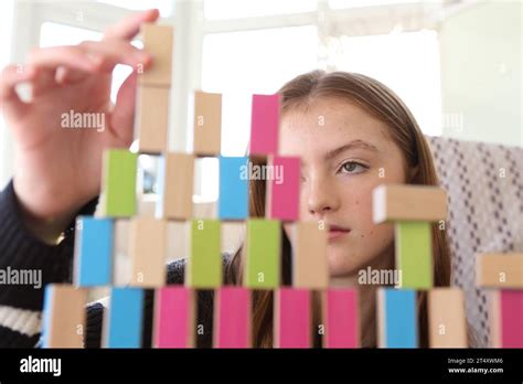 Teenage Girl Constructing A Wall Of Wooden Blocks And Building A Tower