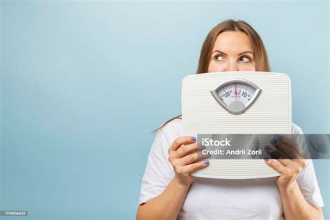 갈색 머리 여자 흰색 비늘을 들고 파란색 배경에 텍스트에 대 한 빈 공간을 향해 찾고 저울에 대한 스톡 사진 및 기타 이미지