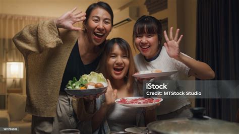 저녁에 집에서 구정 동창회 식사를 위해 함께 모여 셀카 영상 통화를 하는 카메라를 보는 행복한 아시아 친구들 라이프 스타일은 음식을 즐길 수 있습니다 뜨거운 냄비 요리에