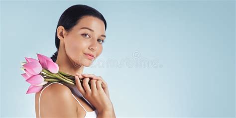 Elegant Woman Posing With Pink Lotus Buds For Skincare And Wellness