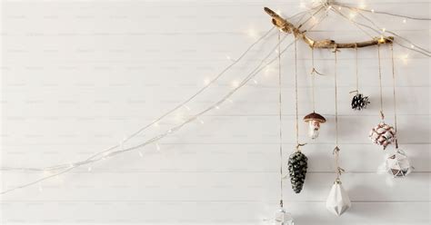 크리스마스 빈티지 장난감은 현대적인 객실 스칸디나비아 미니멀 스타일에 축제 조명이 있는 흰색 벽에 나무 가지에 매달려 있습니다 세련된 유리 장식품 휴일 장식 텍스트를